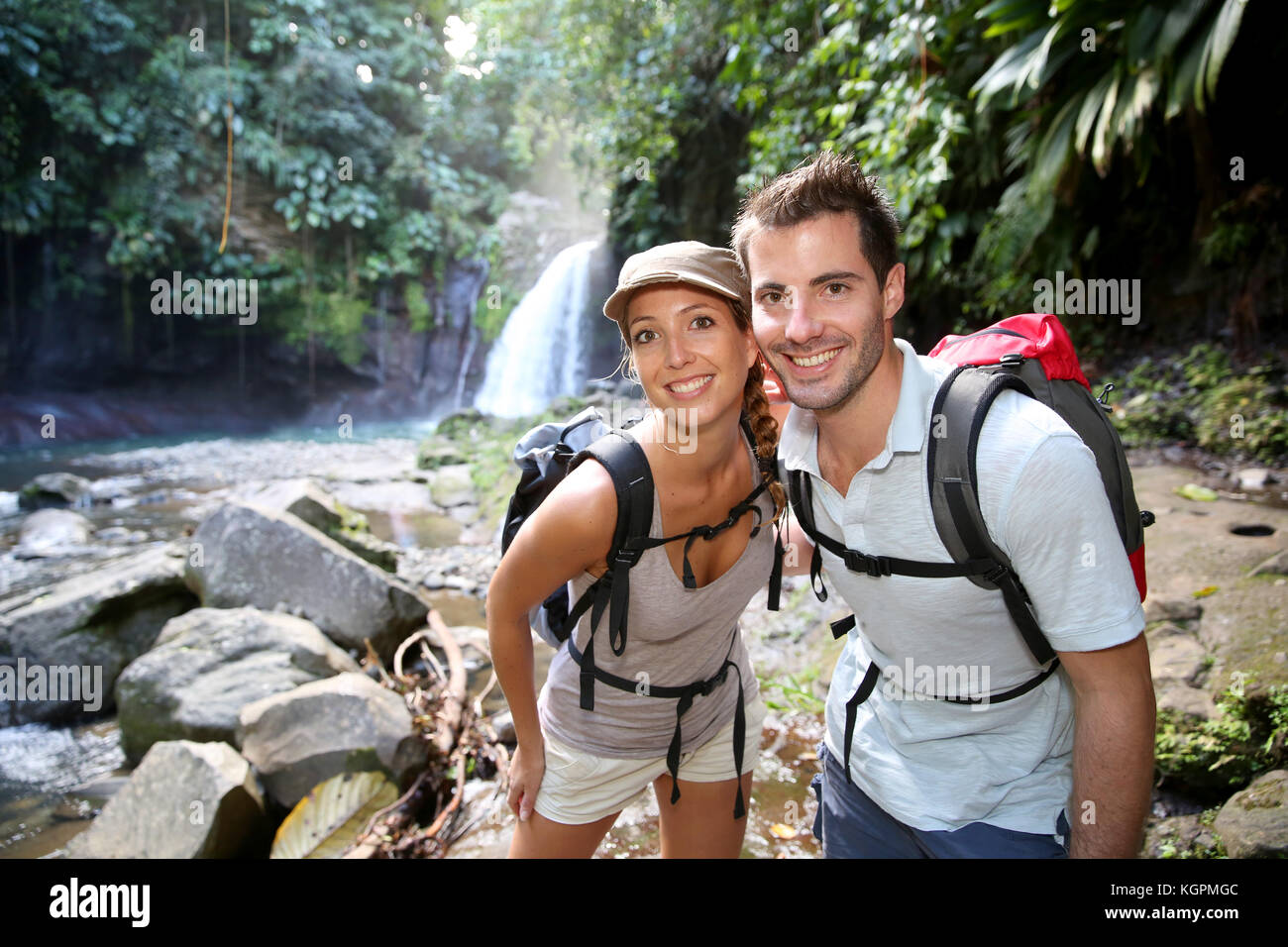 Trekkers reaching waterfall in natural landscape Stock Photo - Alamy