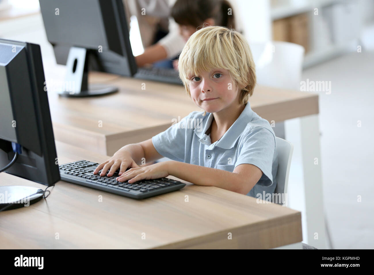 Portrait of school boy sitting in front of computer Stock Photo - Alamy