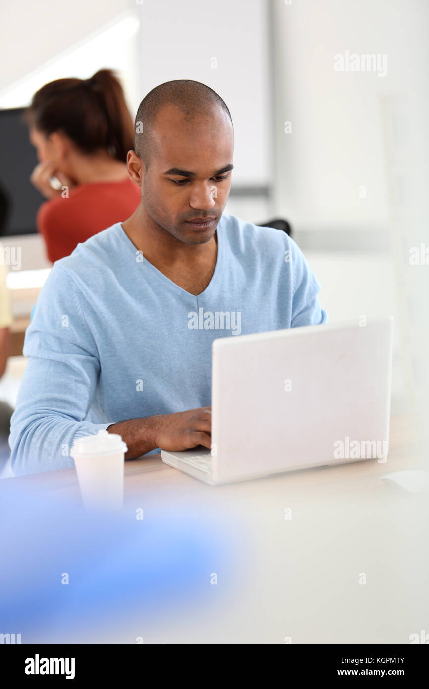 Young man in class working on laptop computer Stock Photo - Alamy
