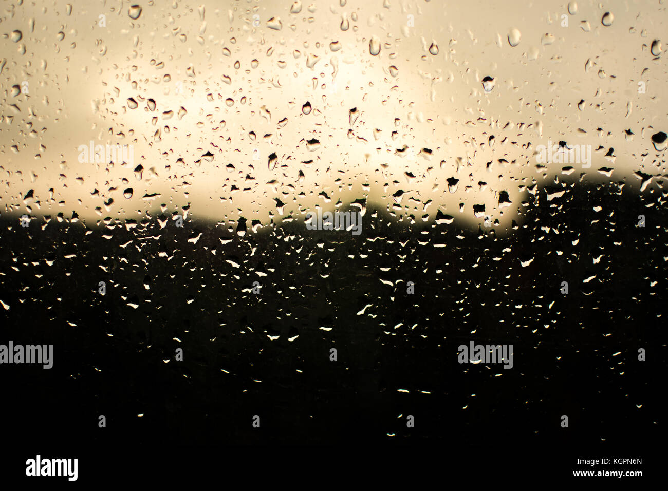 Abstract shot of rain drops on the window of a car with sunset colors ...