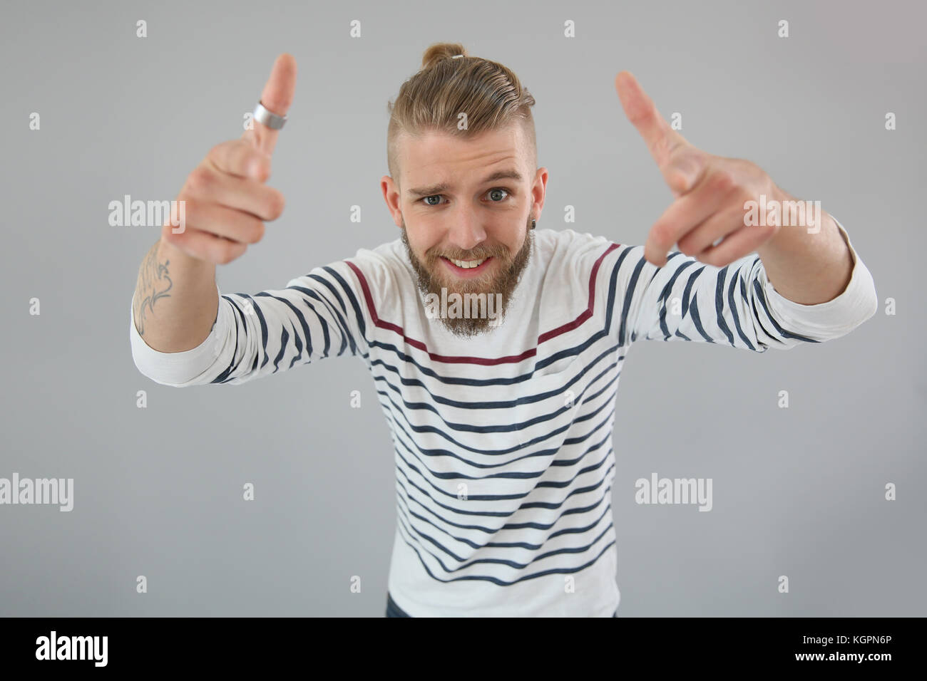 Portrait of trendy guy pointing hands towards calmra Stock Photo - Alamy