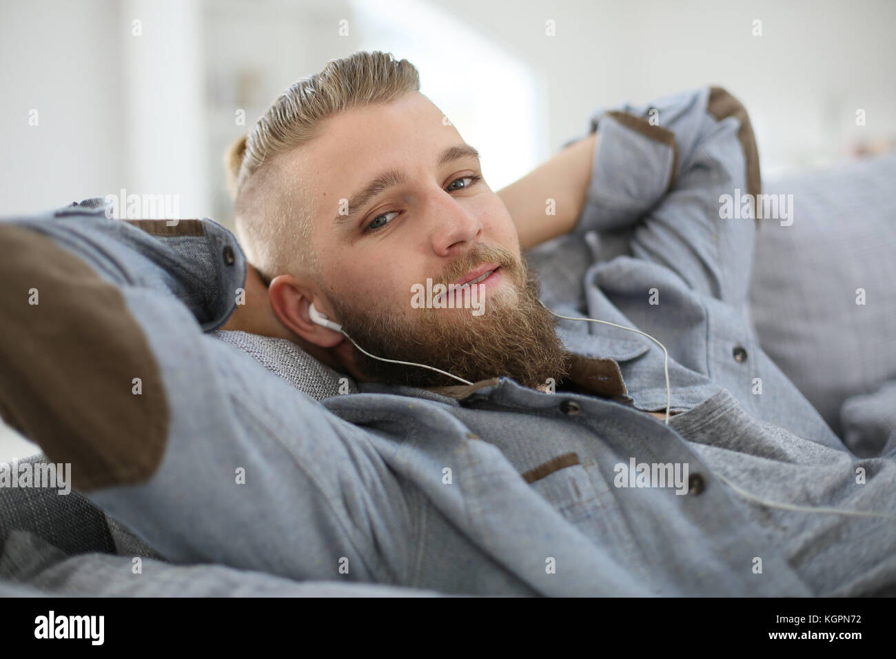 Young man relaxing in sofa, listening to music Stock Photo - Alamy