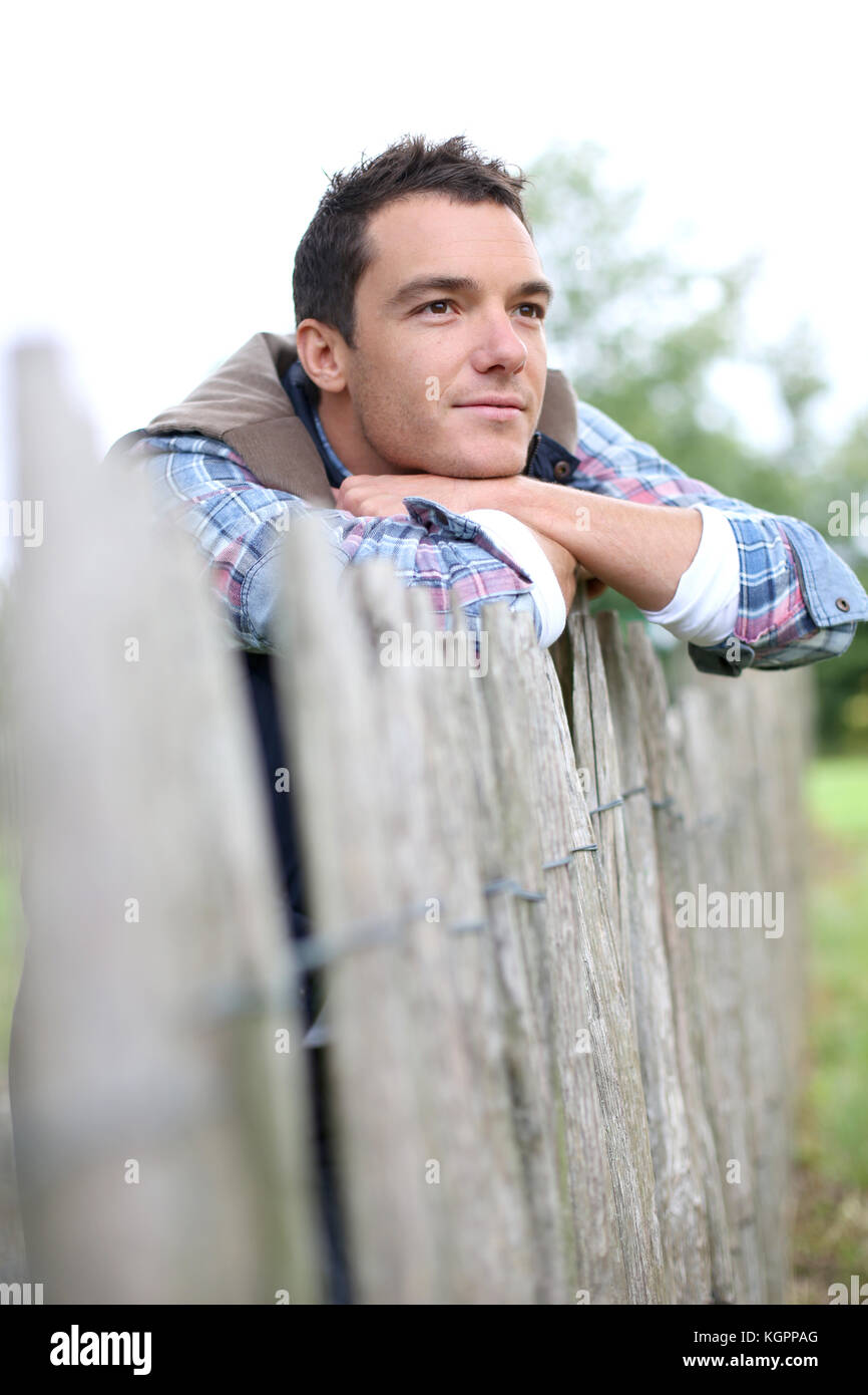 Man in countryside leaning on fence Stock Photo - Alamy