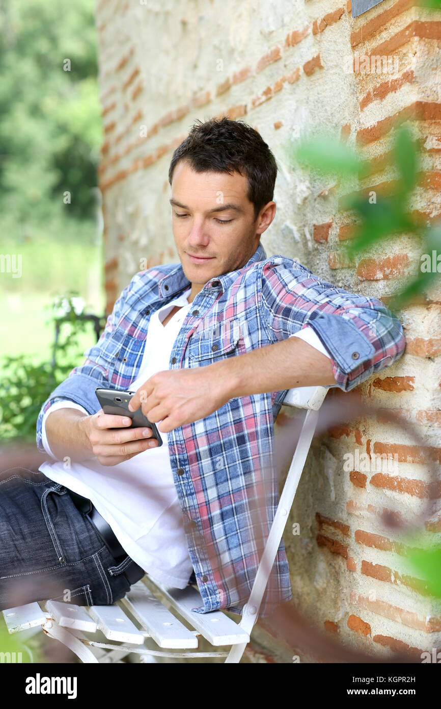 Man relaxing on bench with smartphone Stock Photo - Alamy