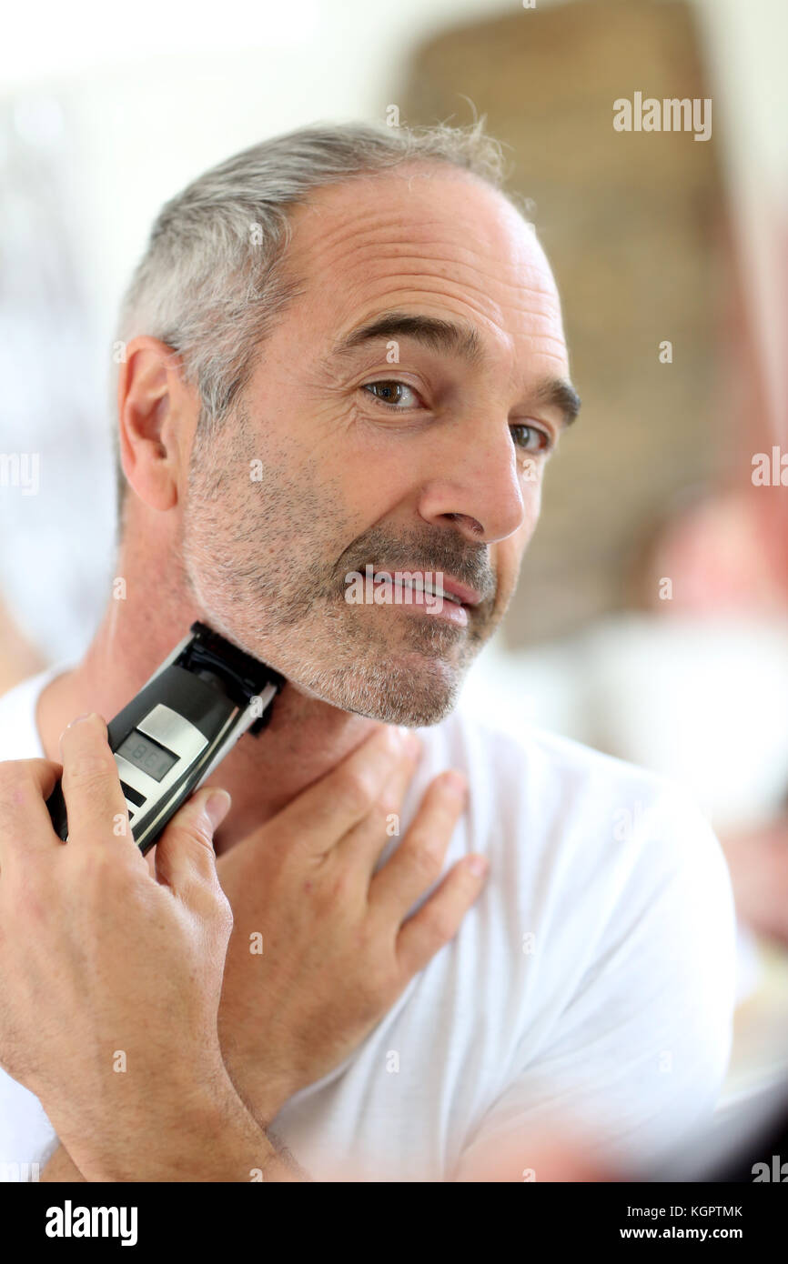 Senior man shaving beard with electric razor Stock Photo - Alamy