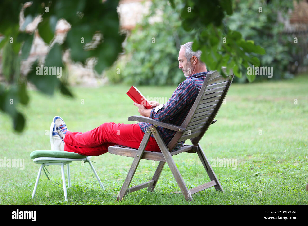 Man reading book in long chair Stock Photo - Alamy