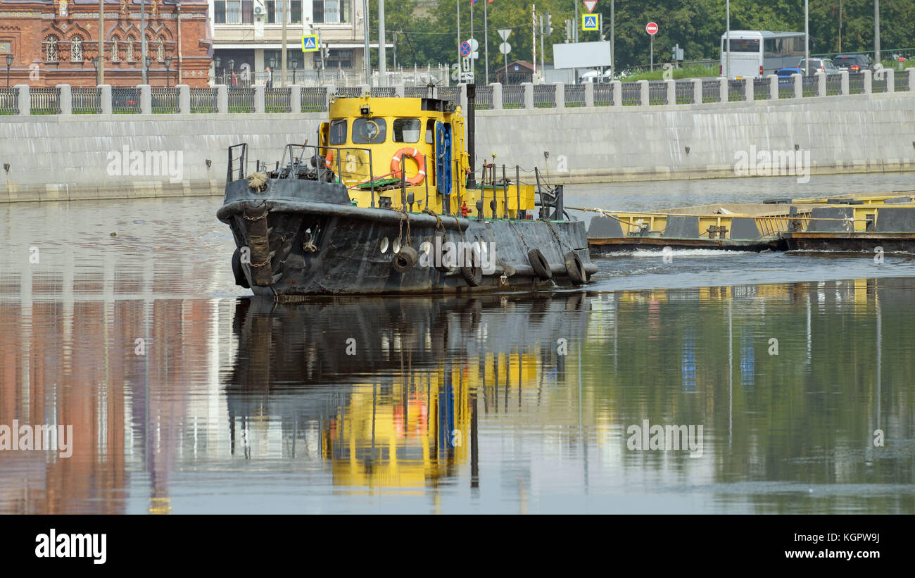 Working boat floats down the river, pulling a cargo Stock Photo - Alamy