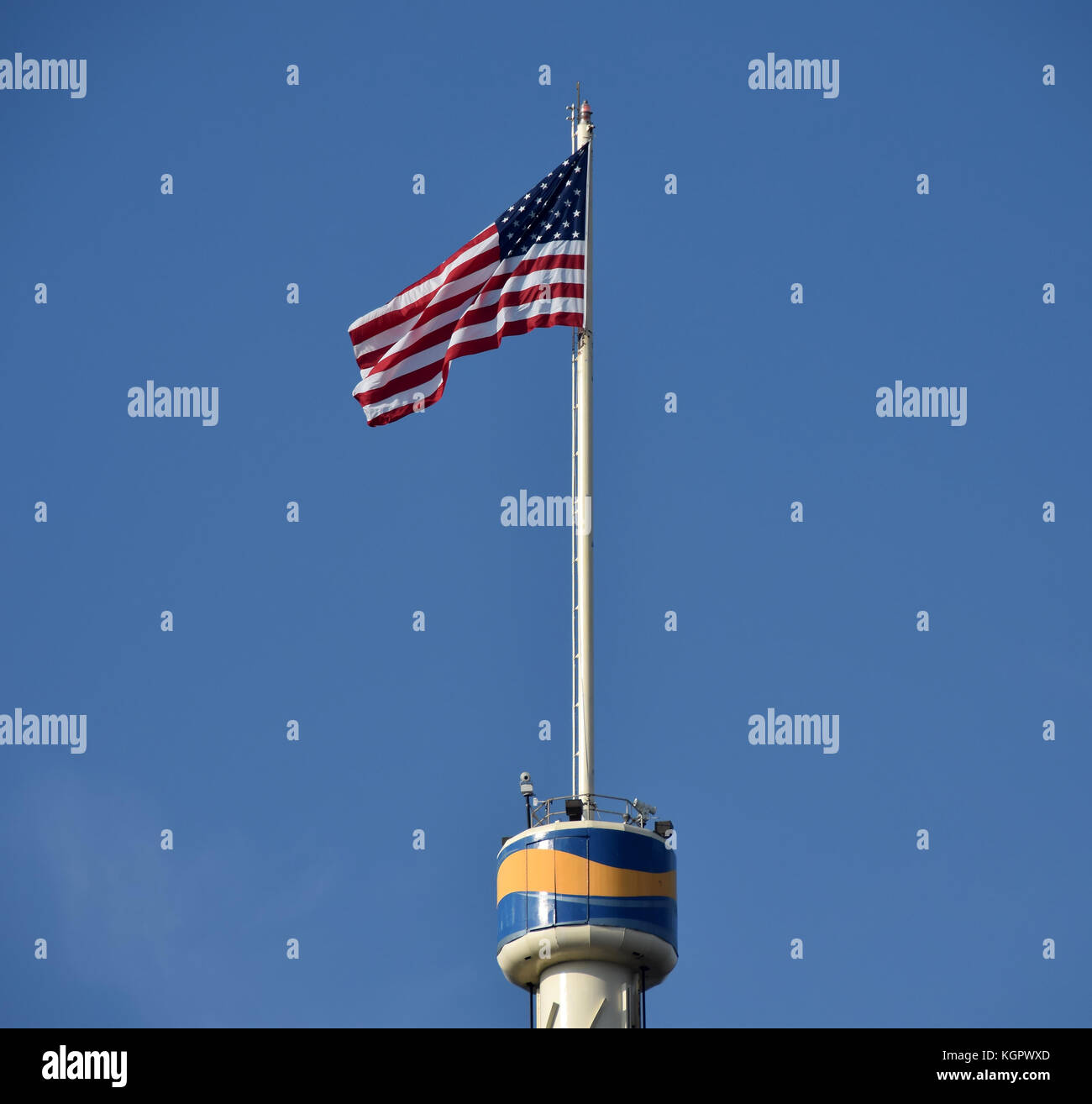 American flag on top of tall tower against blue sky Stock Photo - Alamy
