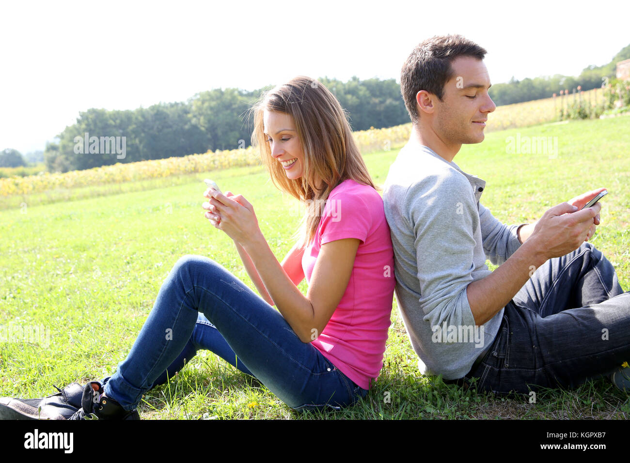 Couple in field playing with smartphone Stock Photo - Alamy