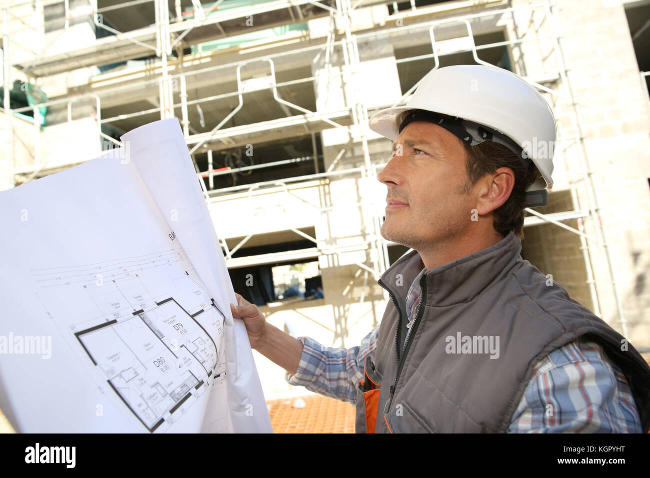 Construction manager on building site holding blueprint Stock Photo - Alamy