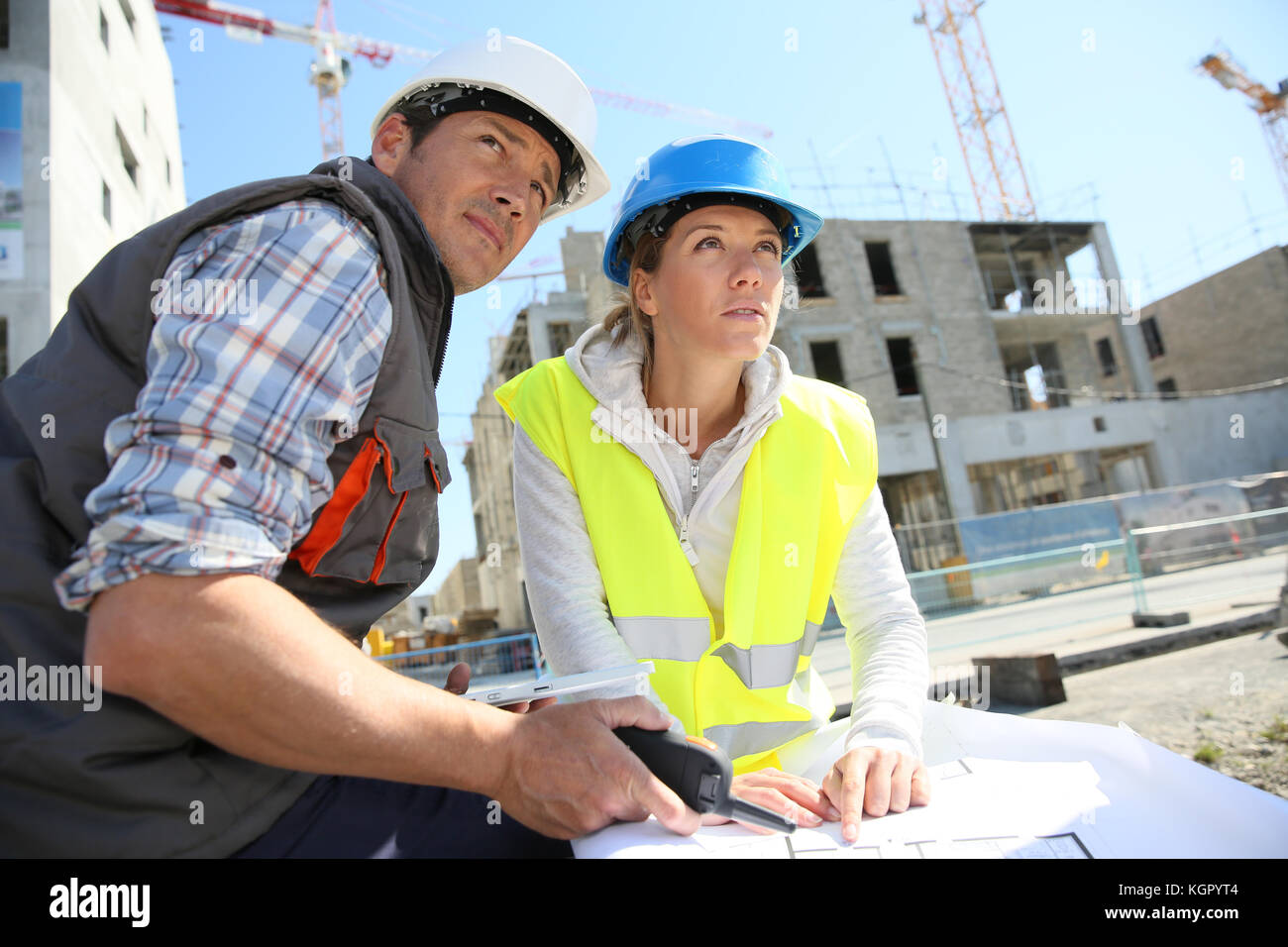 Engineers on building site checking plans Stock Photo - Alamy