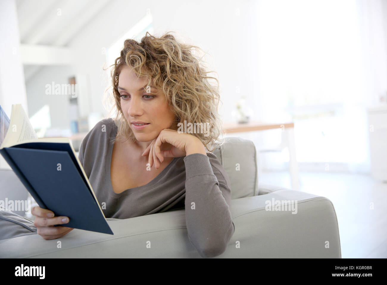 Woman reading book at home in sofa Stock Photo - Alamy