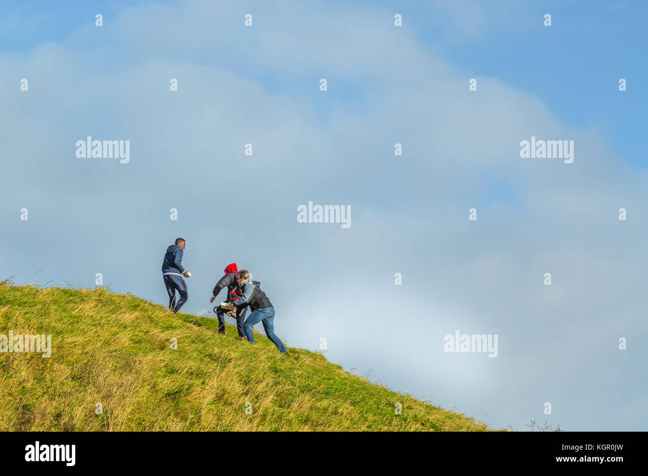Three young men scrambling up a grassy bank Stock Photo - Alamy
