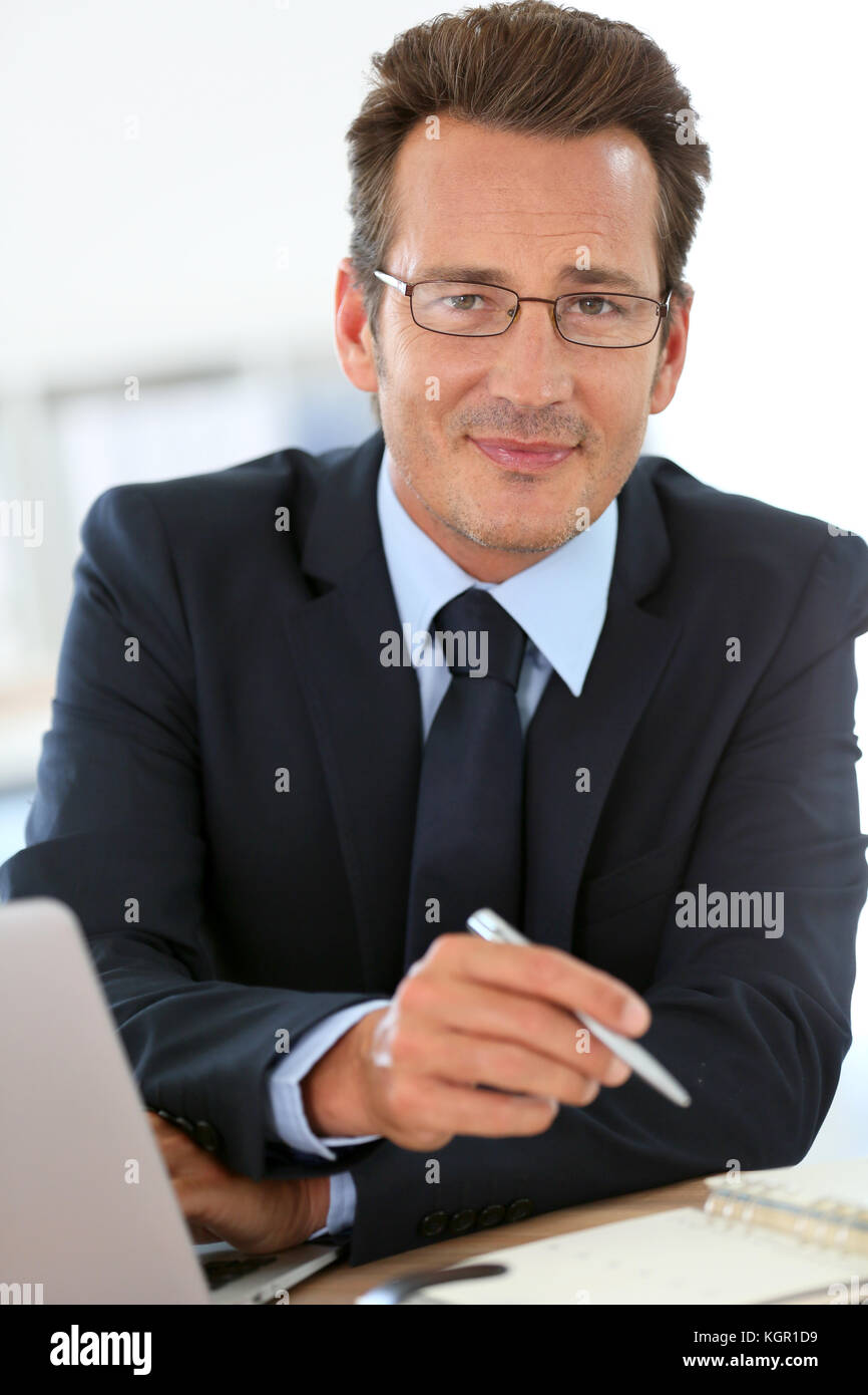 Executive with eyeglasses working on laptop Stock Photo - Alamy
