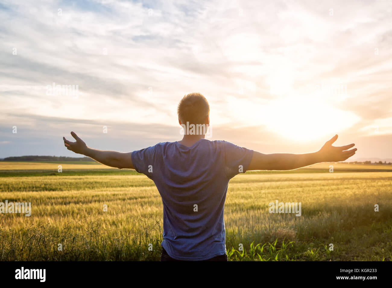 Man standing in an open field at sunset with open arms - embracing ...