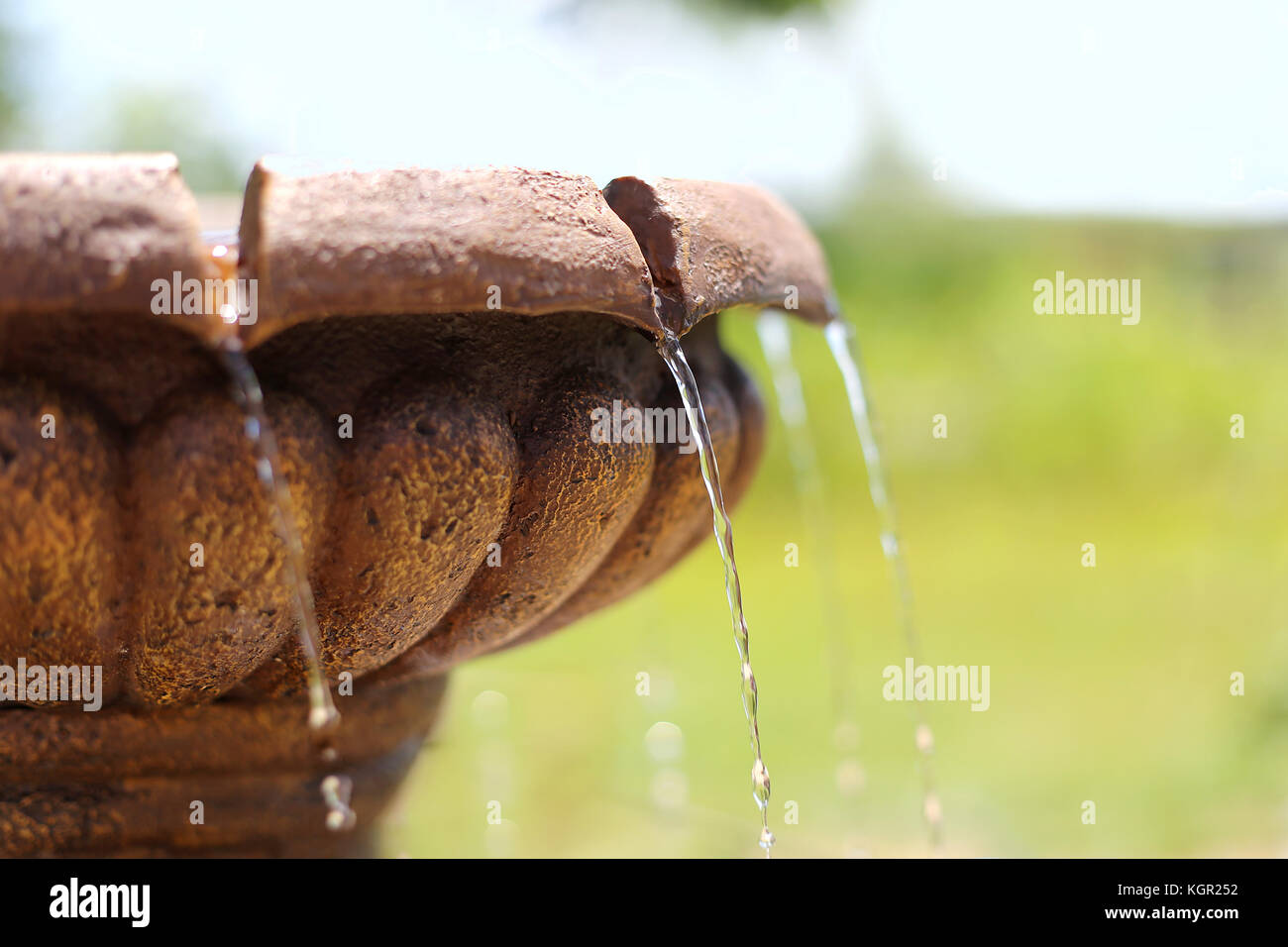 Close up on the flow of water from an old stone garden foutain in a ...