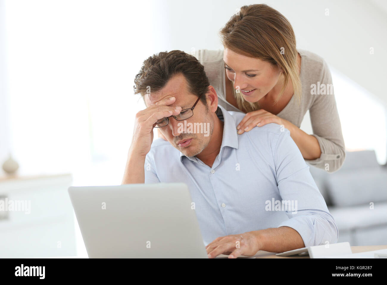 Woman trying to relax worried husband in front of laptop Stock Photo ...