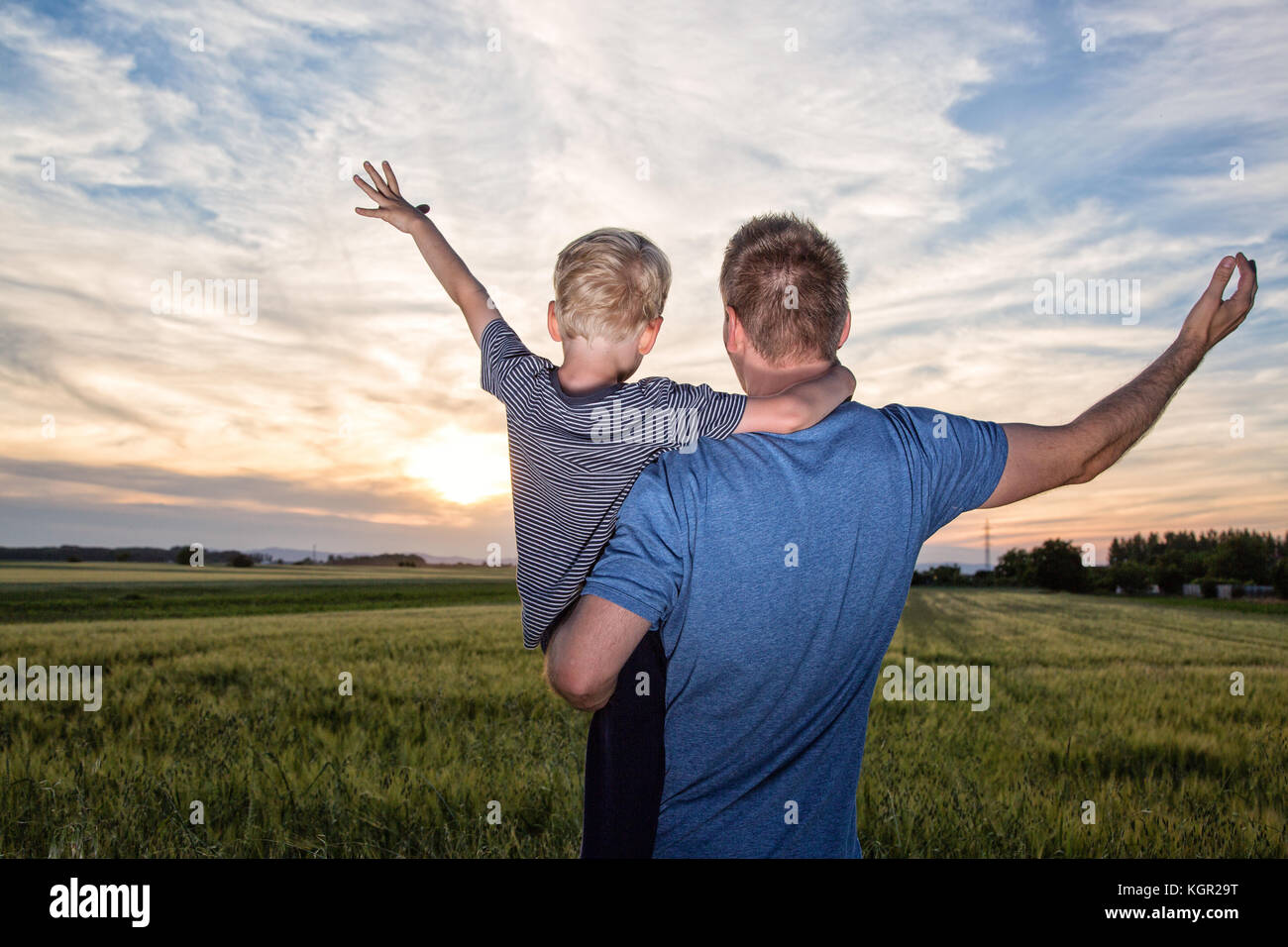 Father and son standing in an open field at sunset with open arms ...
