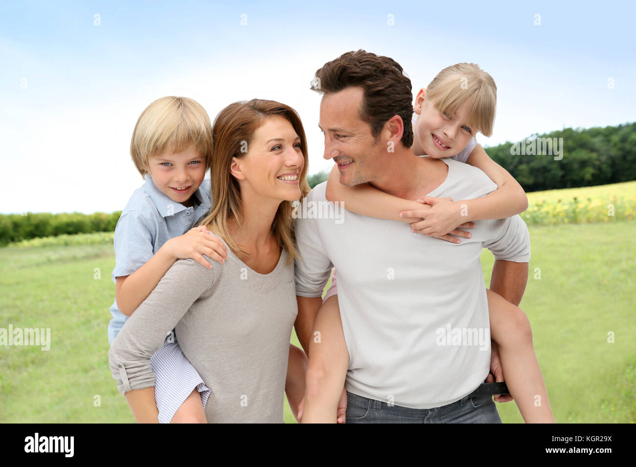 Parents giving piggyback ride to kids in countryside Stock Photo - Alamy