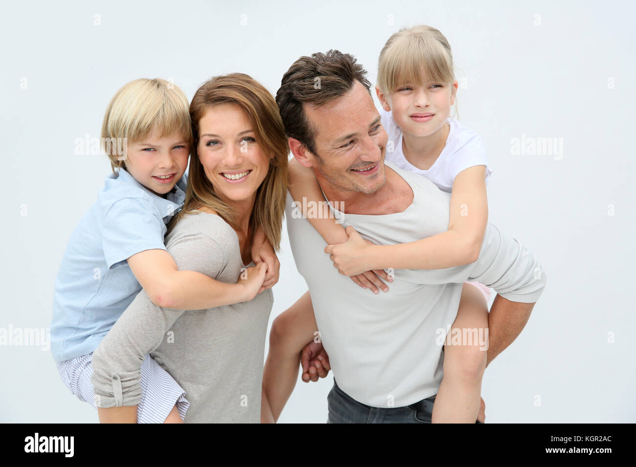 Parents giving piggyback ride to kids Stock Photo - Alamy