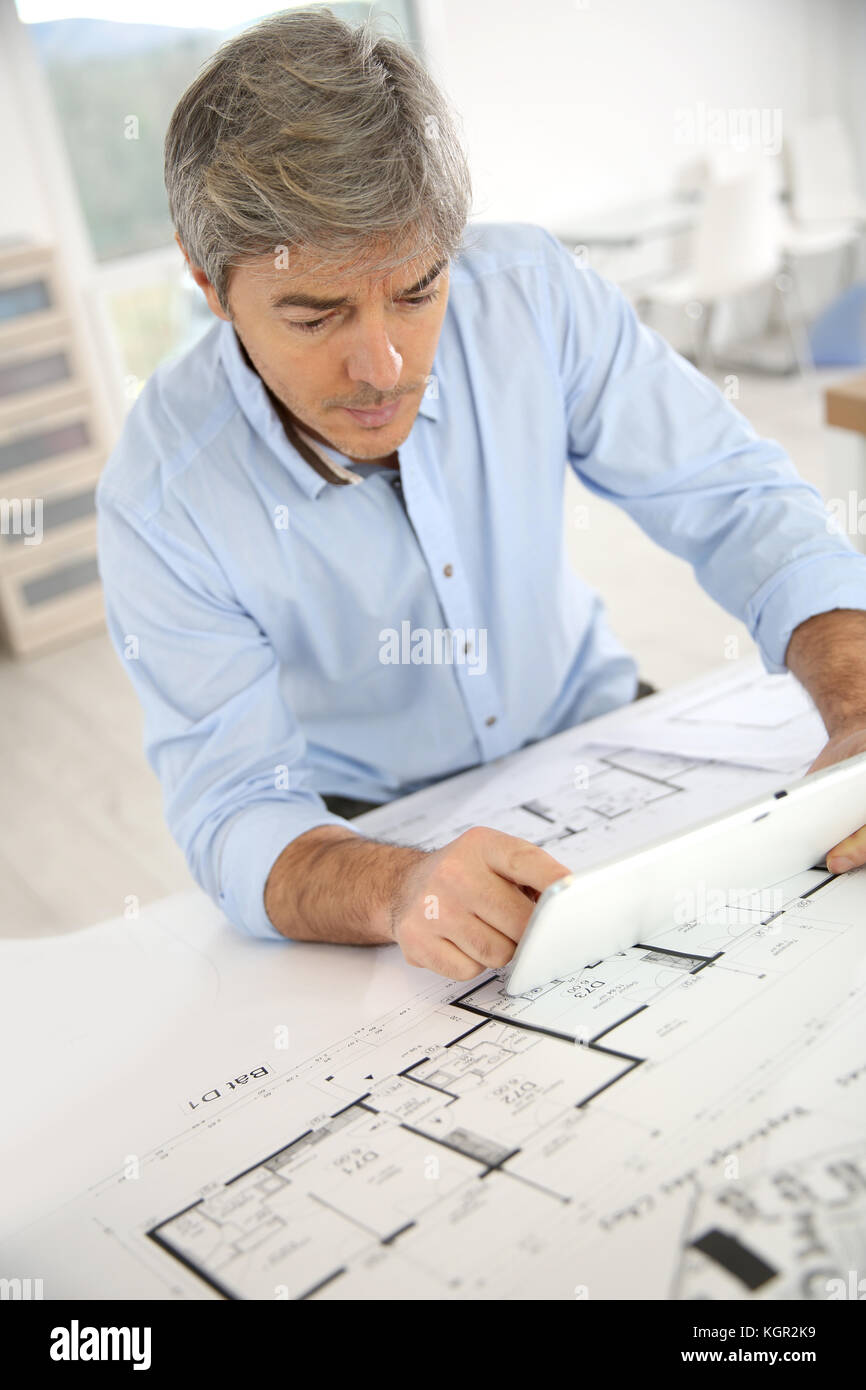 Architect working on blueprint in office Stock Photo - Alamy