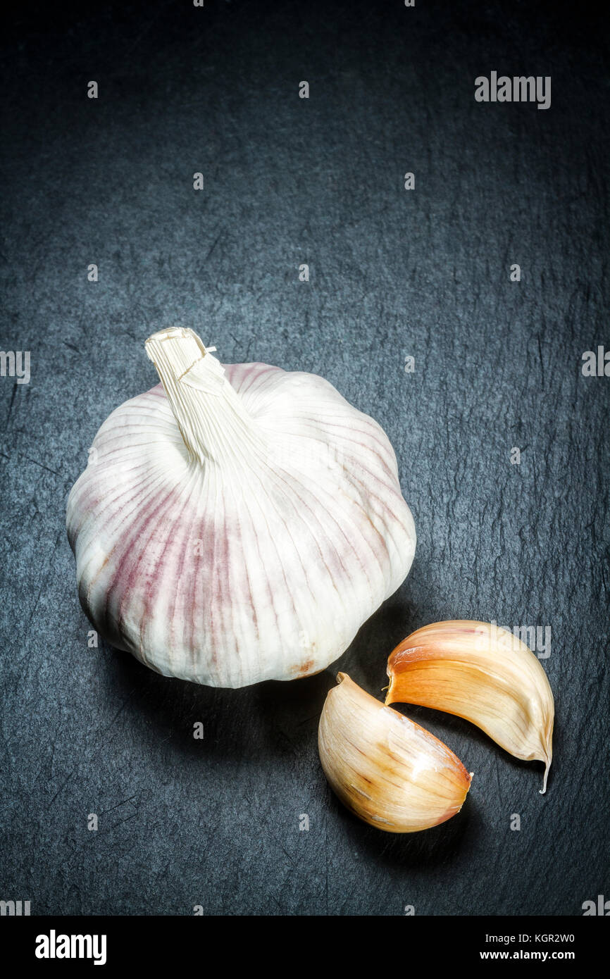 Garlic bulb and cloves (Allium sativum) on a black slate surface Stock ...