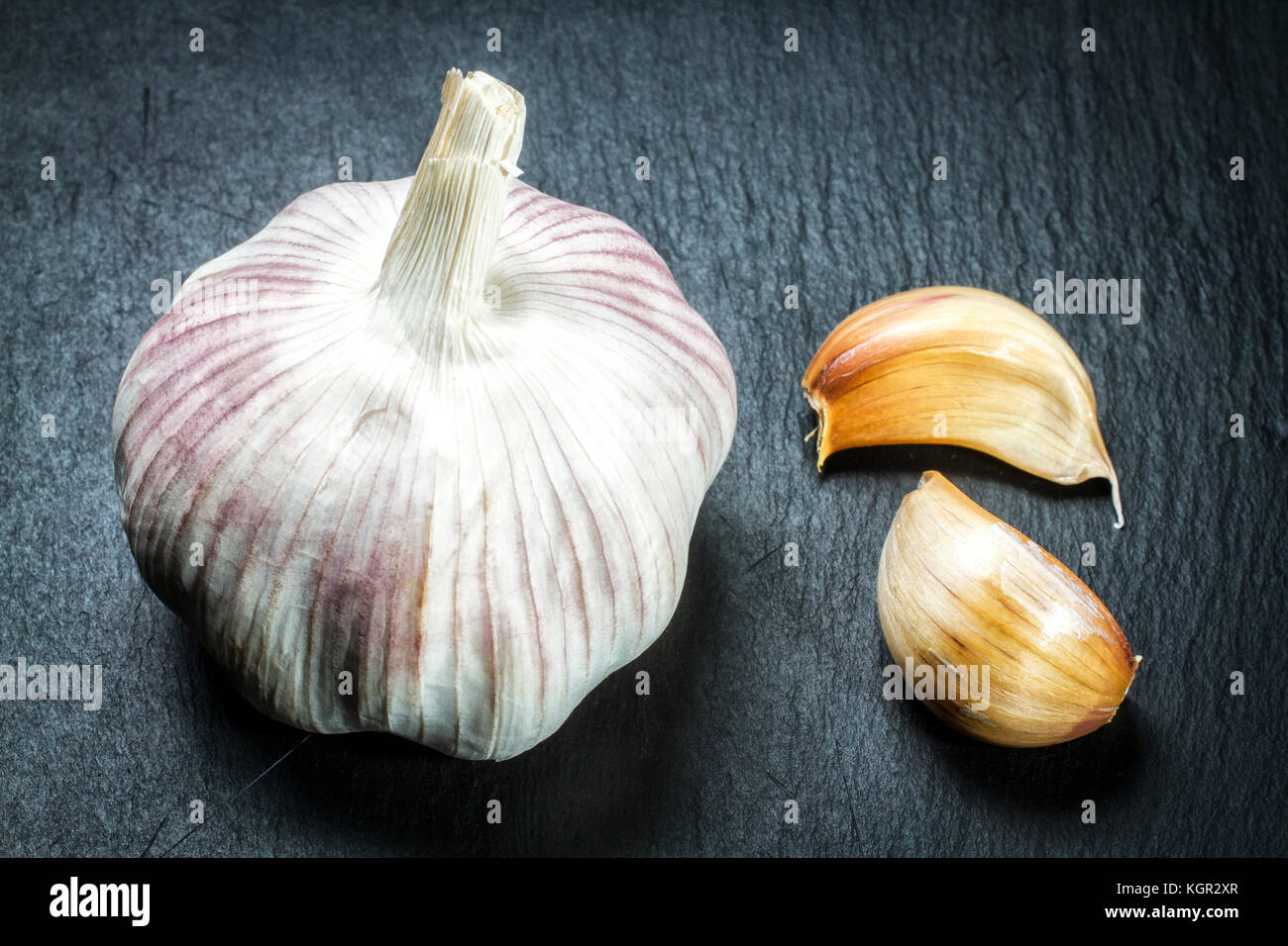 Garlic bulb and cloves (Allium sativum) on a black slate surface Stock ...