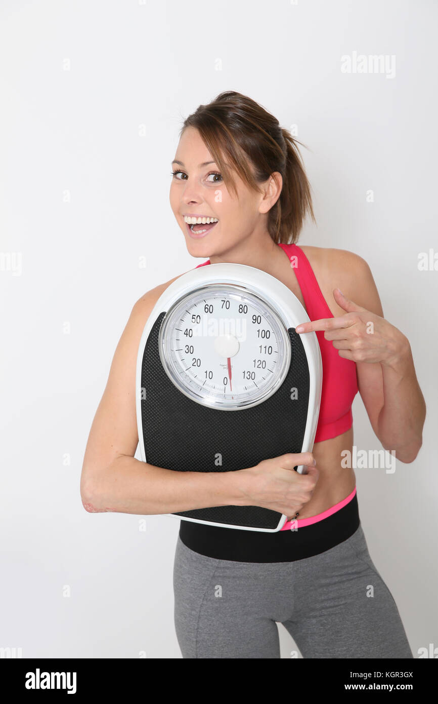 Cheerful girl in fitness holding scale, isolated Stock Photo - Alamy