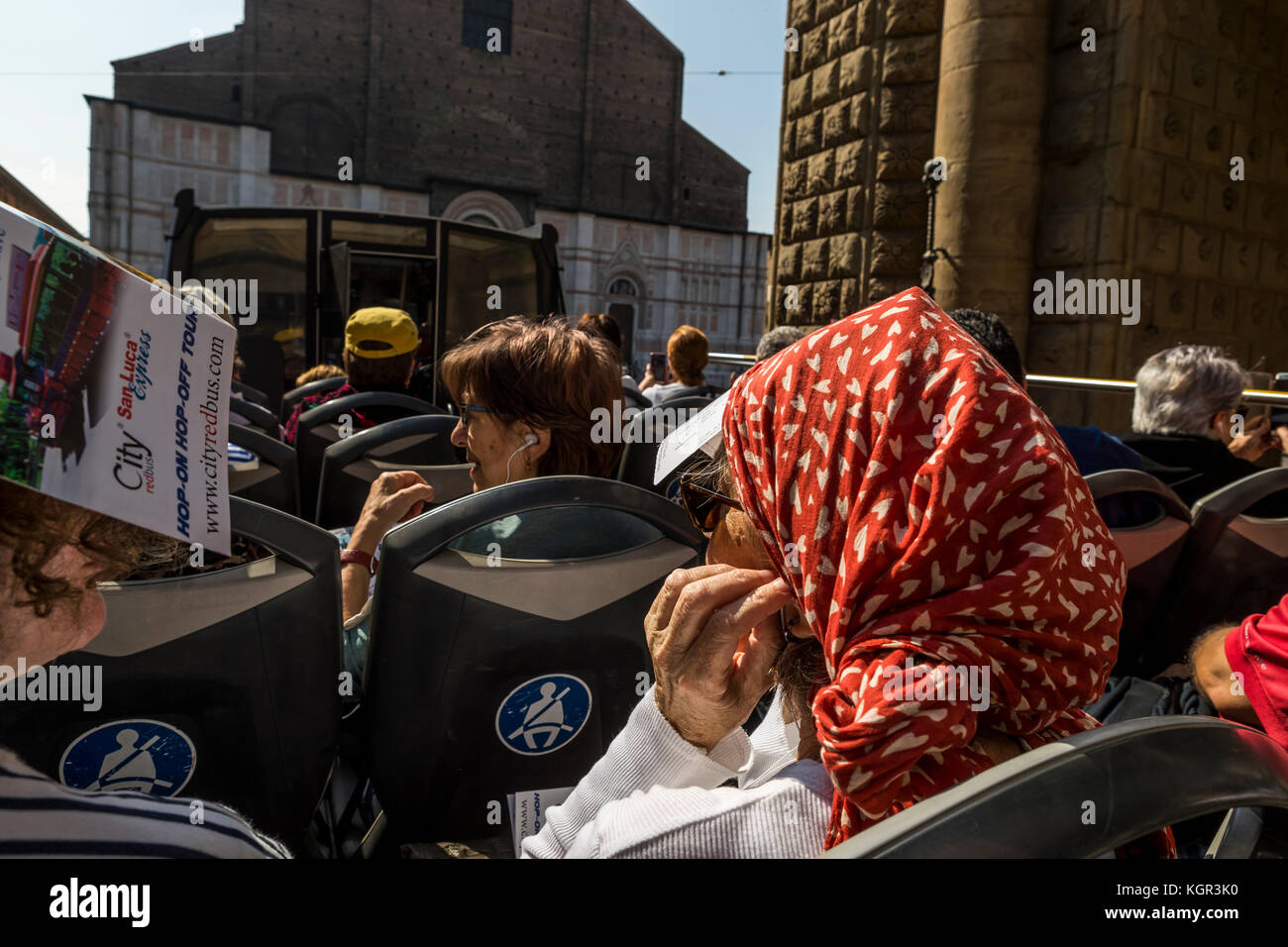Tourists and visitors take the red bus tour through Piazza Maggiore ...