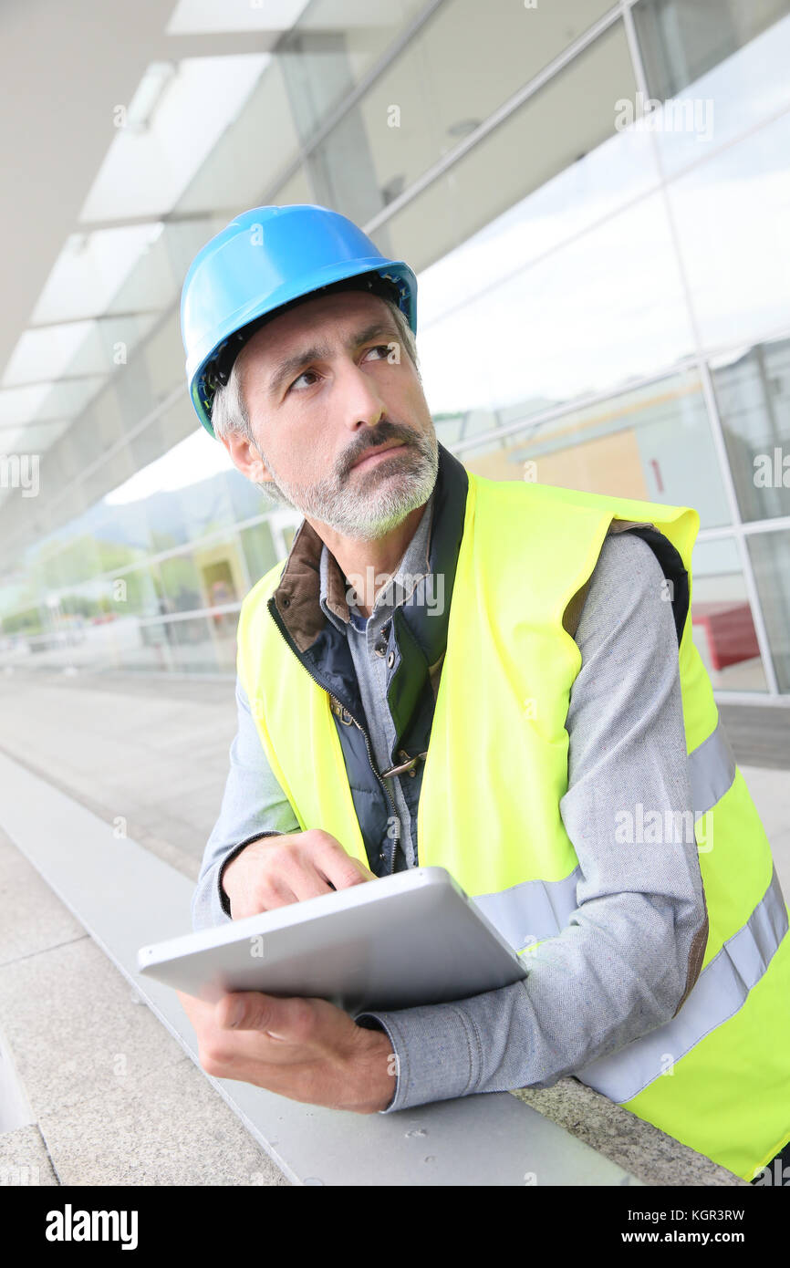 Engineer with hard hat using tablet outside building Stock Photo - Alamy