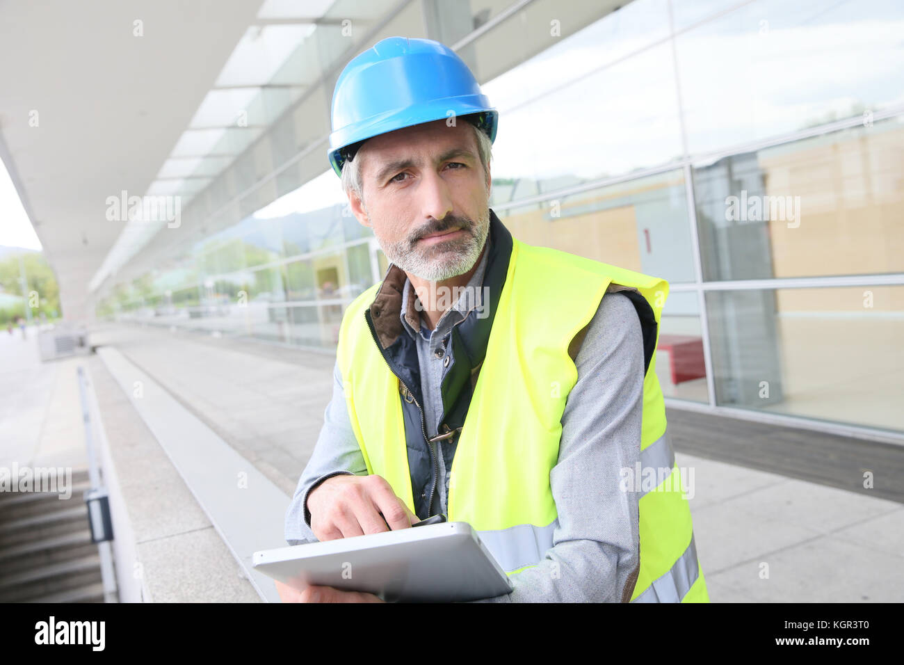 Engineer with hard hat using tablet outside building Stock Photo - Alamy