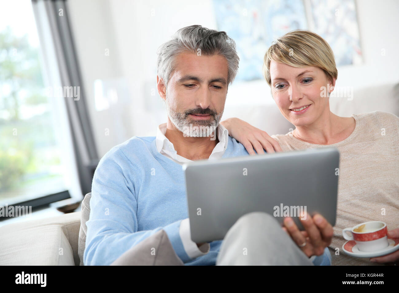 Middle-aged couple websurfing on internet with touchpad Stock Photo - Alamy
