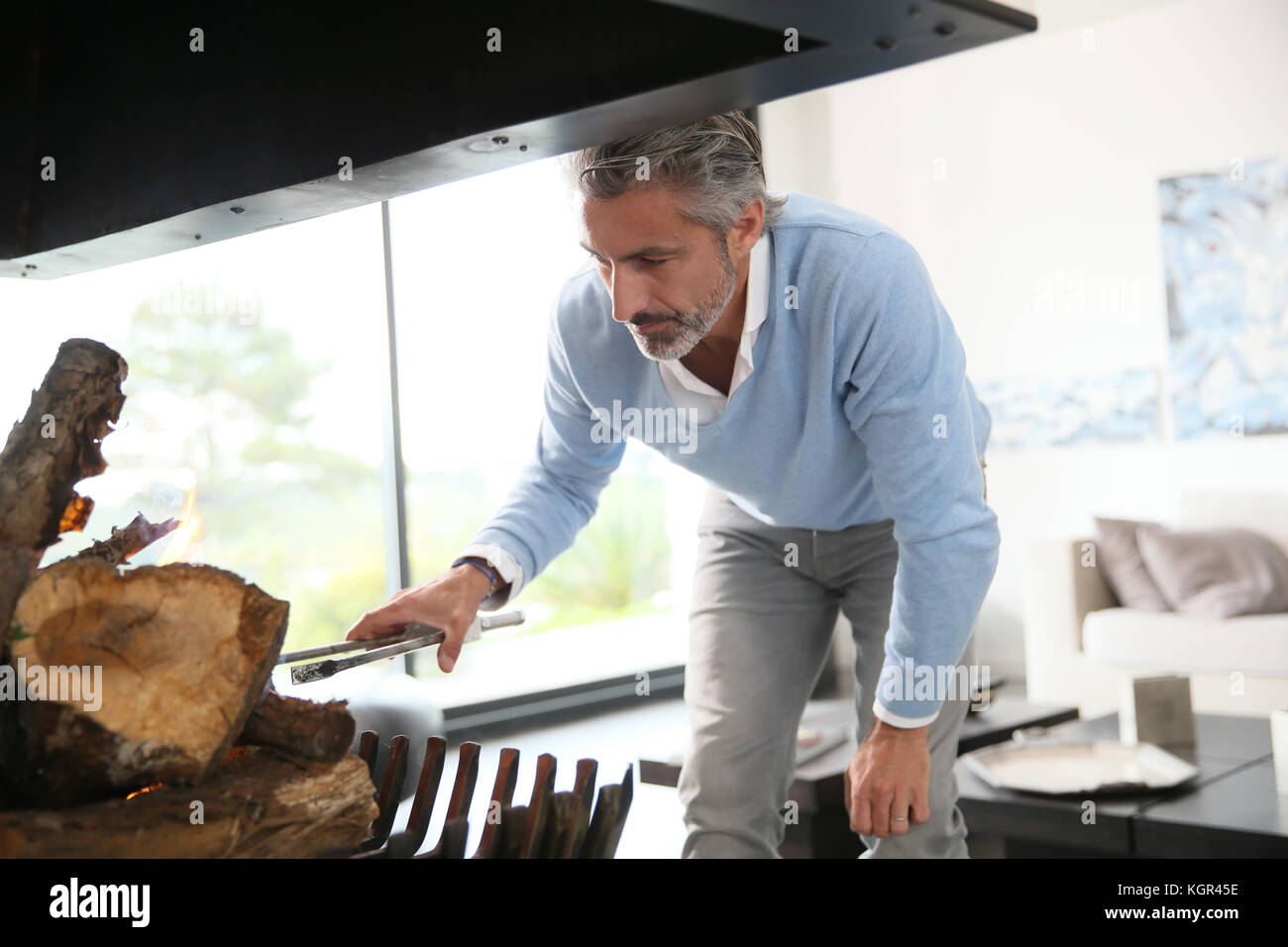 Mature man in contemporary house preparing fire Stock Photo - Alamy