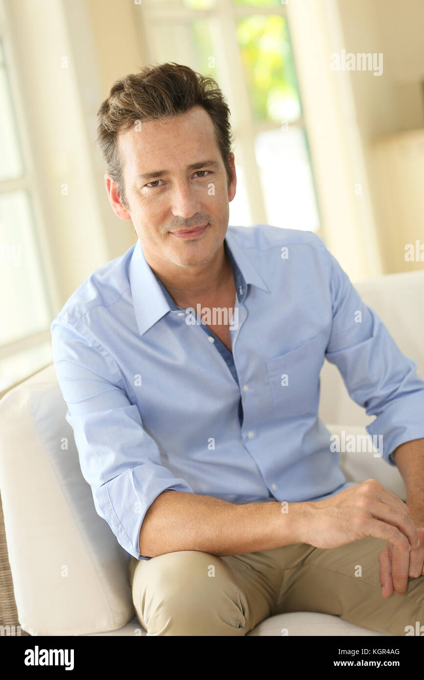 Portrait of single middle-aged man sitting in sofa Stock Photo - Alamy