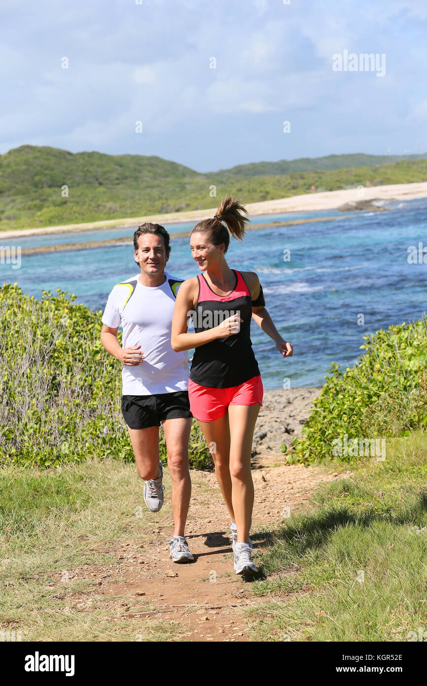 Couple running by the sea on track Stock Photo - Alamy