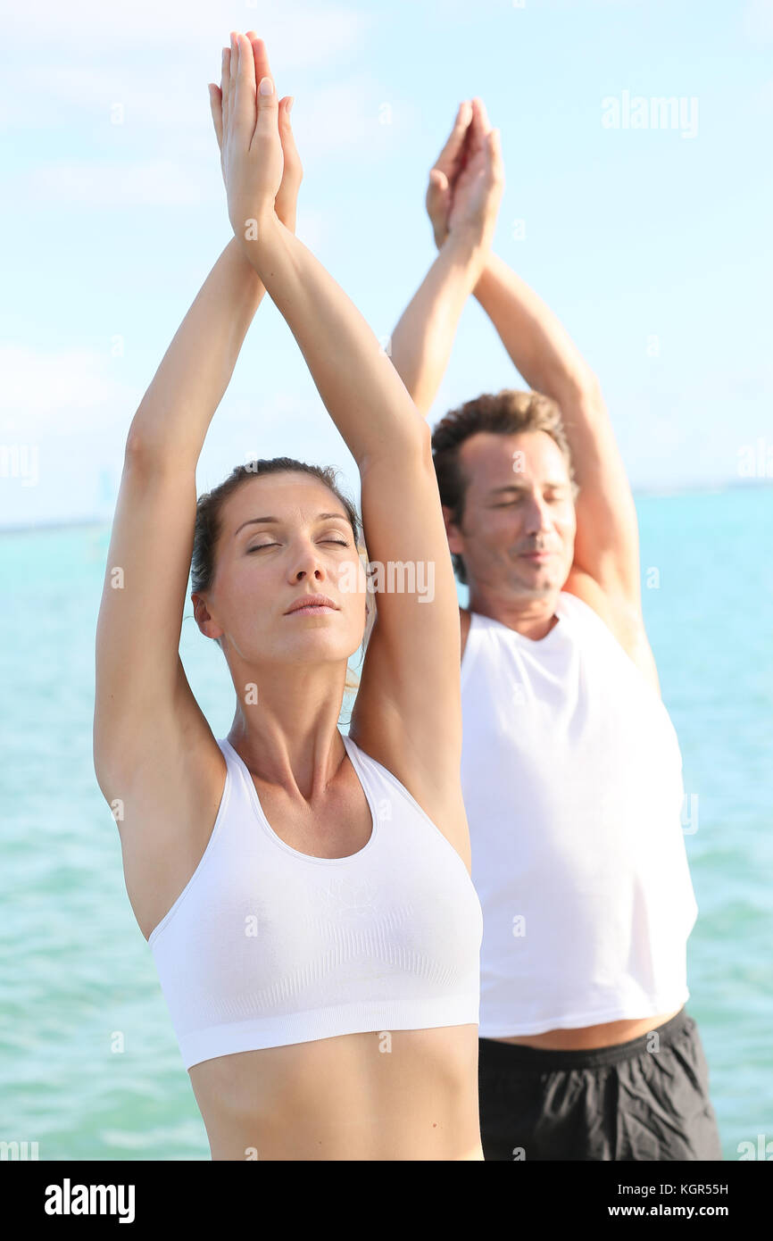 Couple doing yoga and relaxation exercises by the sea Stock Photo - Alamy