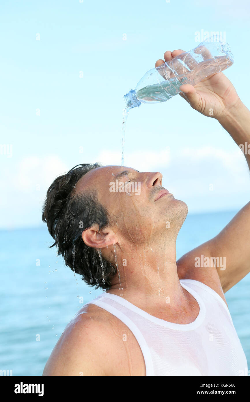 Handsome man pouring water from bottle on his face Stock Photo - Alamy