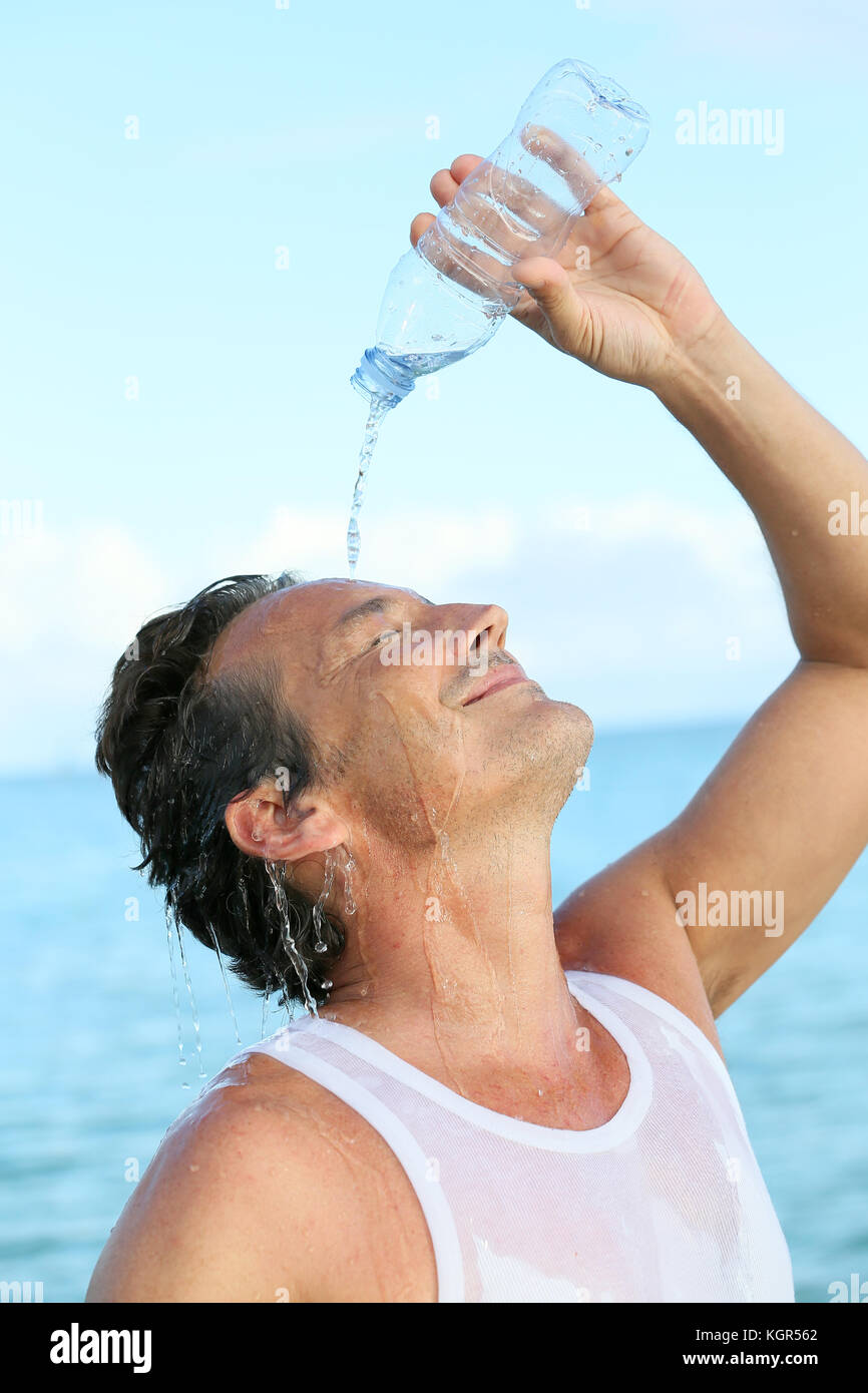 Handsome man pouring water from bottle on his face Stock Photo - Alamy