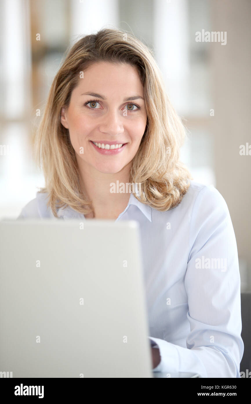 Smiling office worker in front of laptop computer Stock Photo - Alamy
