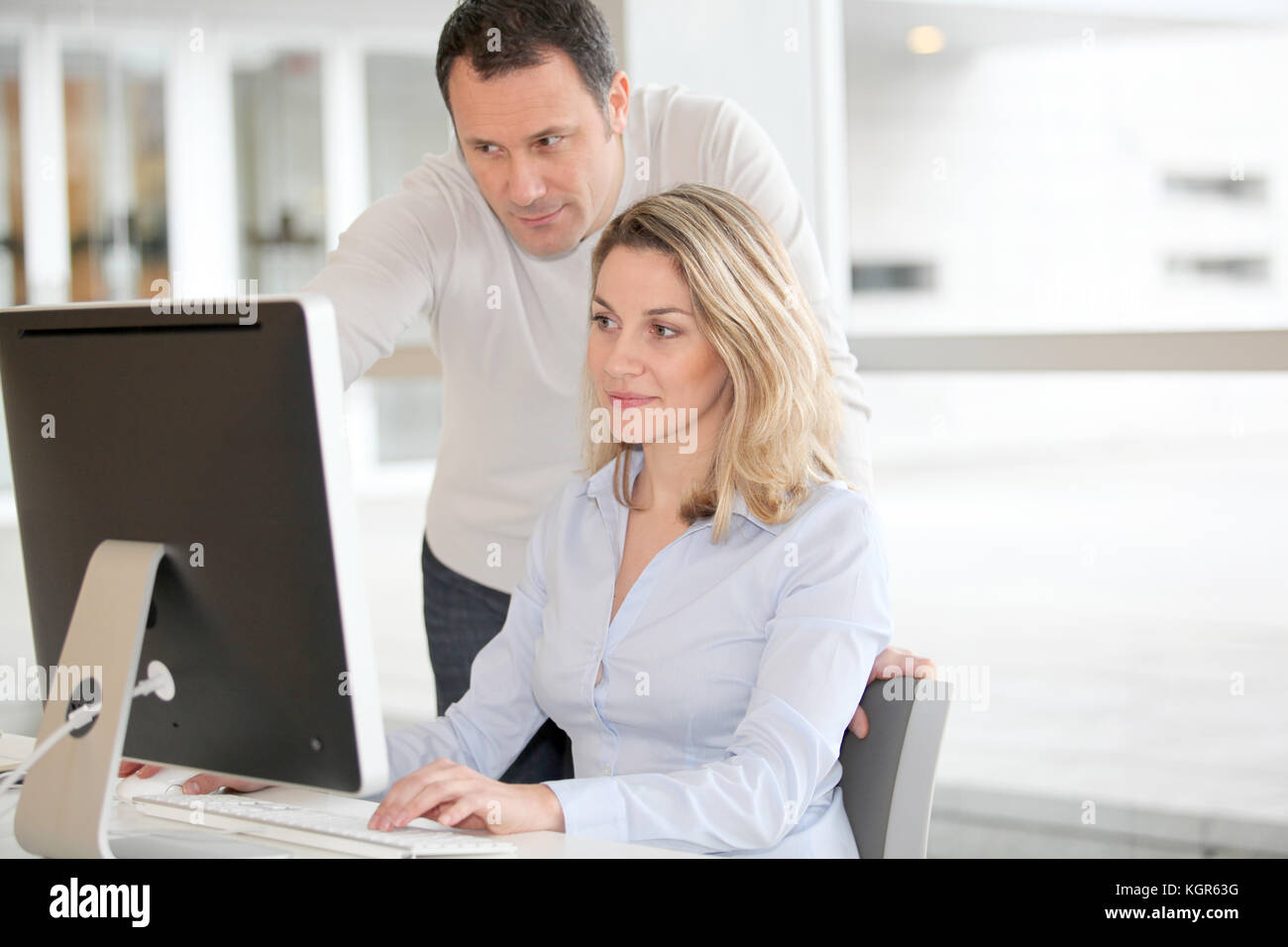 Office workers in front of desktop computer Stock Photo - Alamy