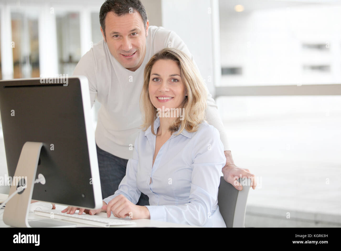 Office workers in front of desktop computer Stock Photo - Alamy