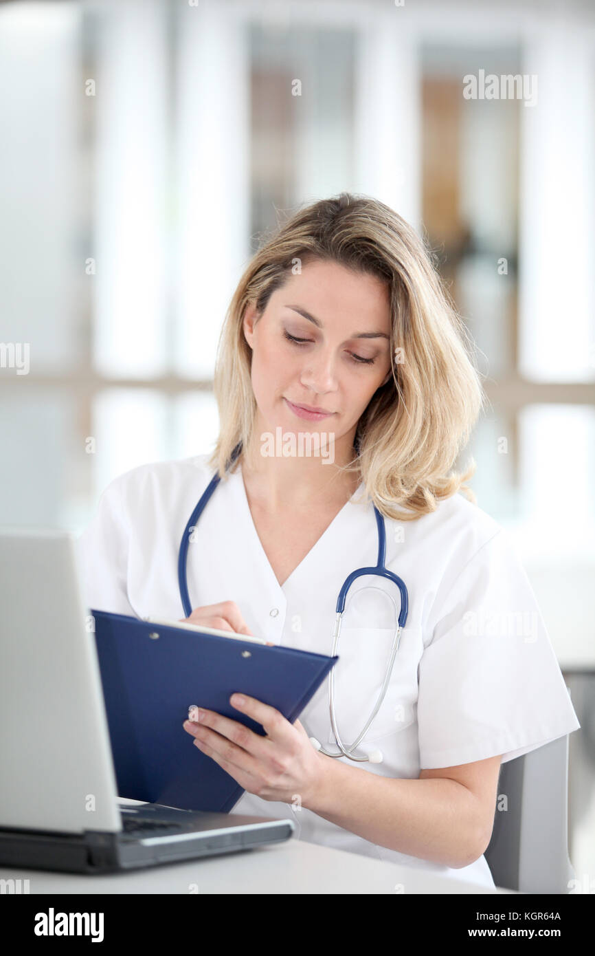 Beautiful nurse in hospital writing on notepad Stock Photo - Alamy