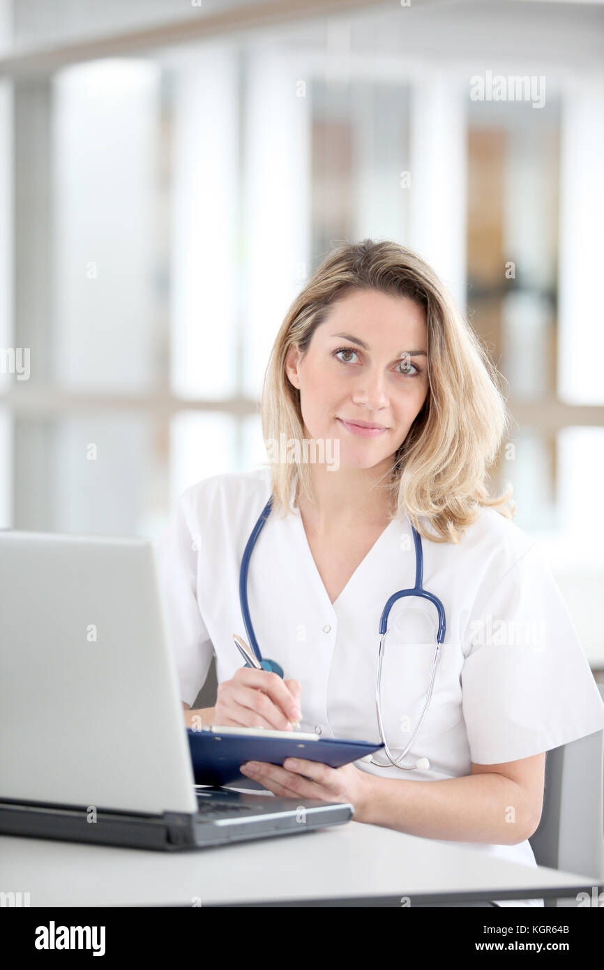 Beautiful nurse in hospital writing on notepad Stock Photo - Alamy