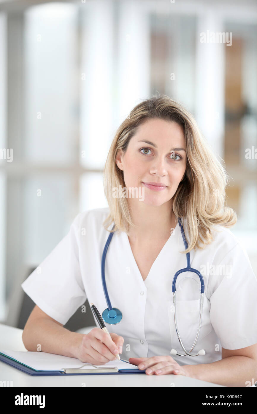 Beautiful nurse in hospital writing on notepad Stock Photo - Alamy