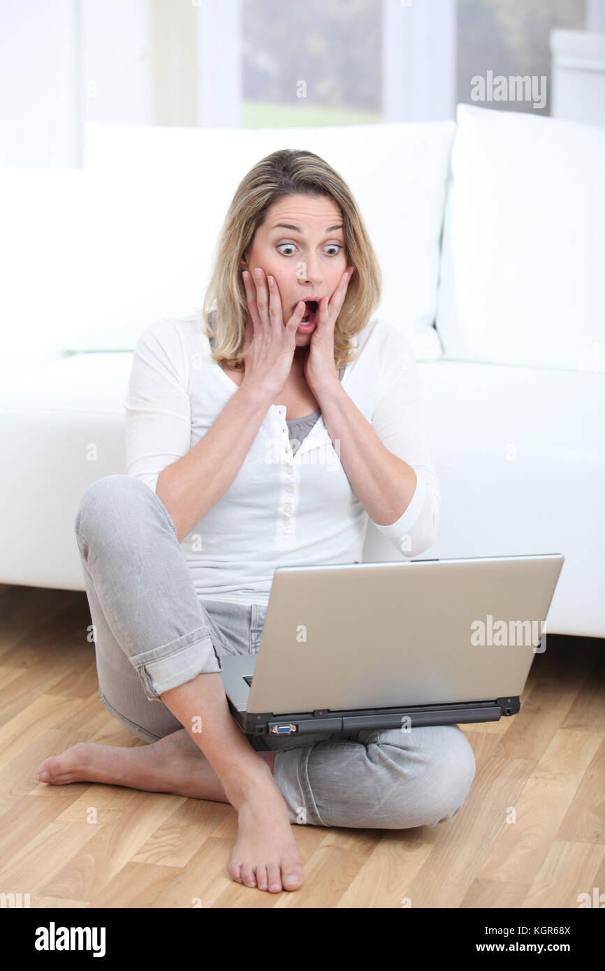 Surprised woman in front of laptop computer Stock Photo - Alamy
