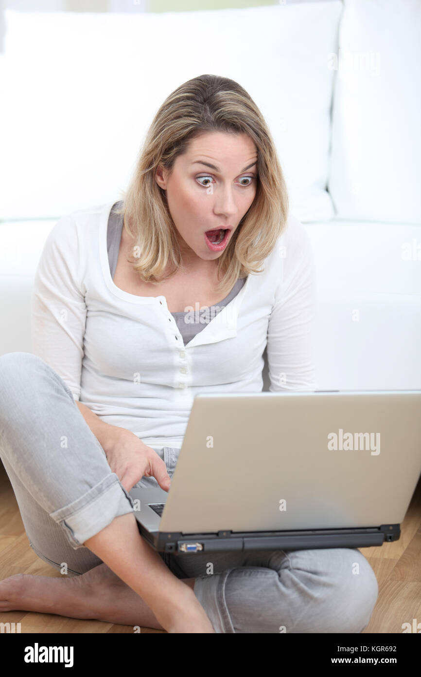Surprised woman in front of laptop computer Stock Photo - Alamy