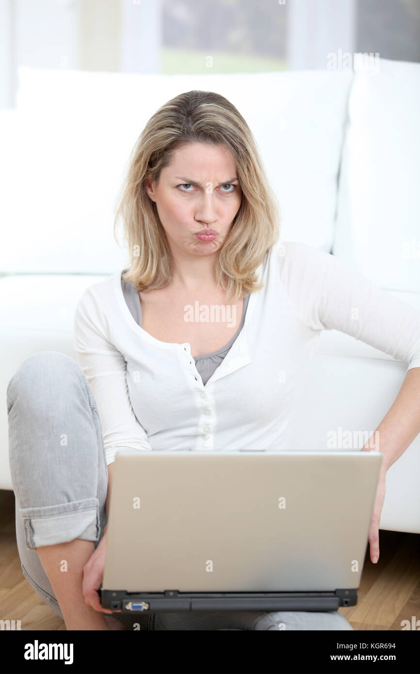 Woman with mad look using laptop computer Stock Photo - Alamy