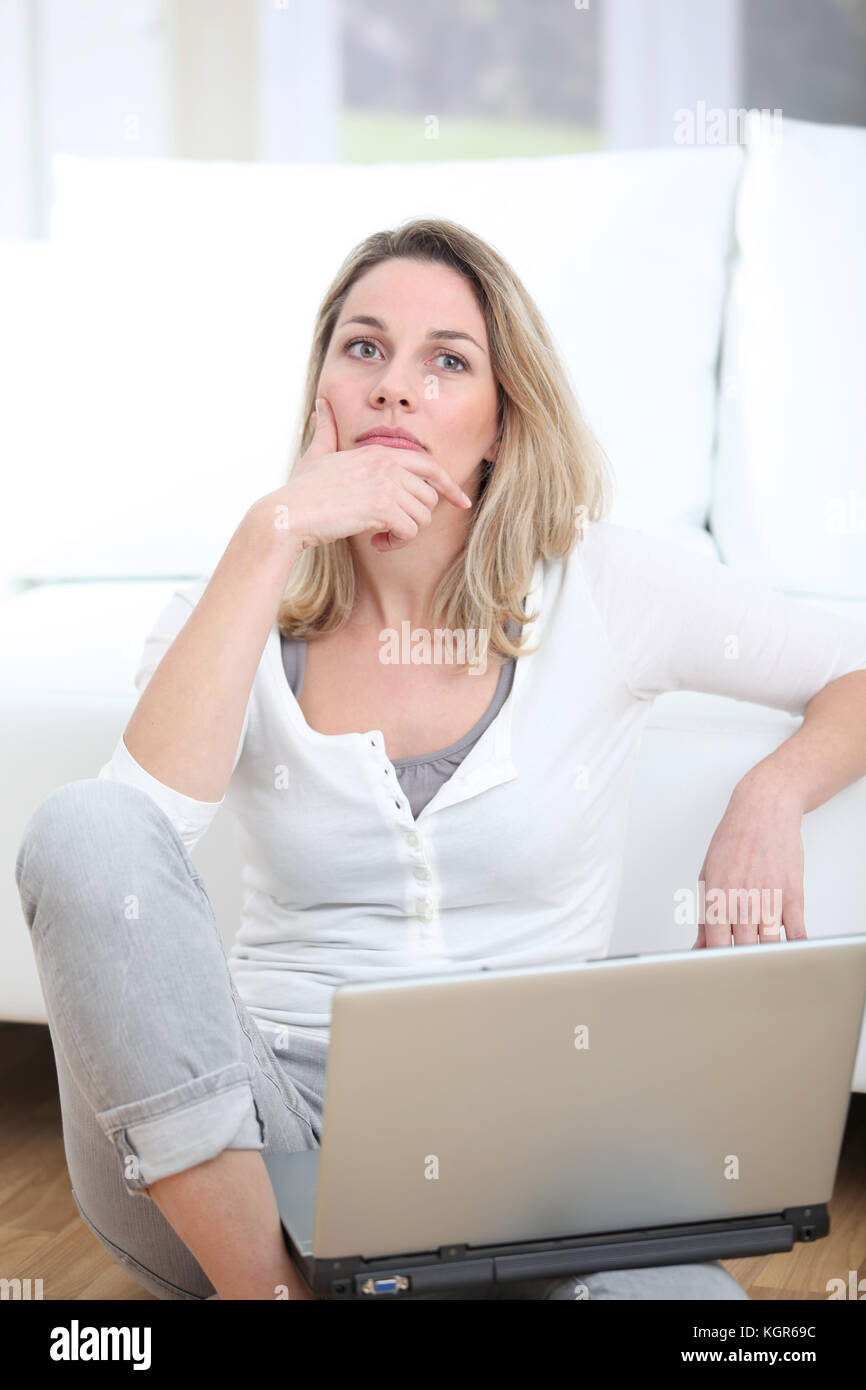 Woman with thoughtful look using laptop computer Stock Photo - Alamy