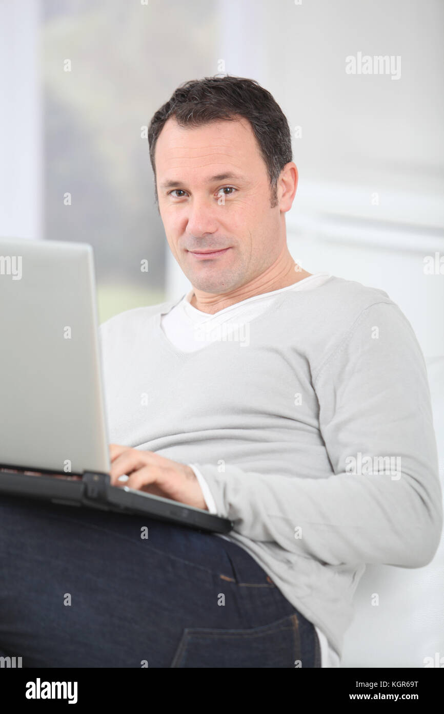 Man sitting in couch using laptop computer Stock Photo - Alamy