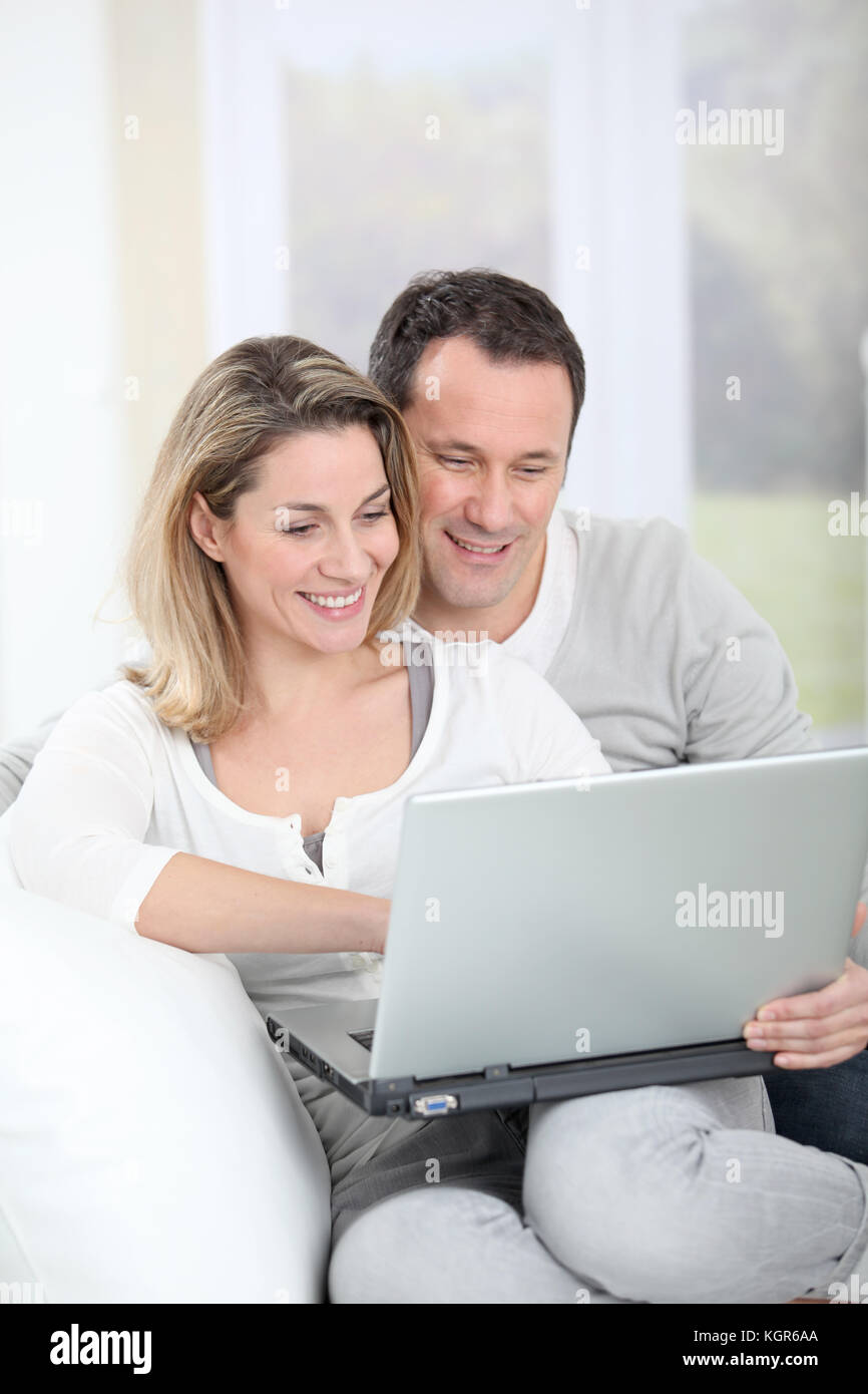 Couple sitting in sofa with laptop computer Stock Photo - Alamy